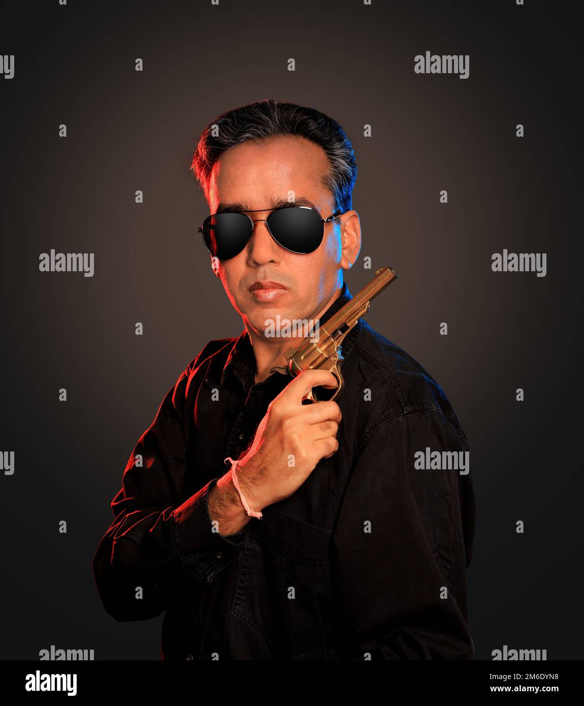 Indian Man with sunglasses and gun on dark background Stock Photo - Alamy