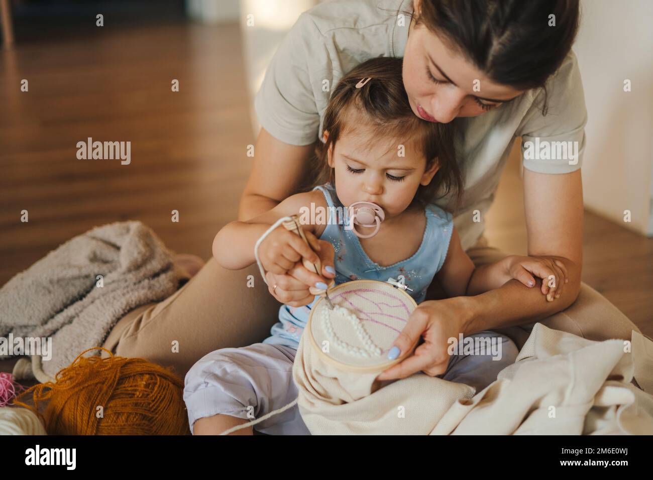 Mother with baby girl working with punch needles and embroidery hoop ...