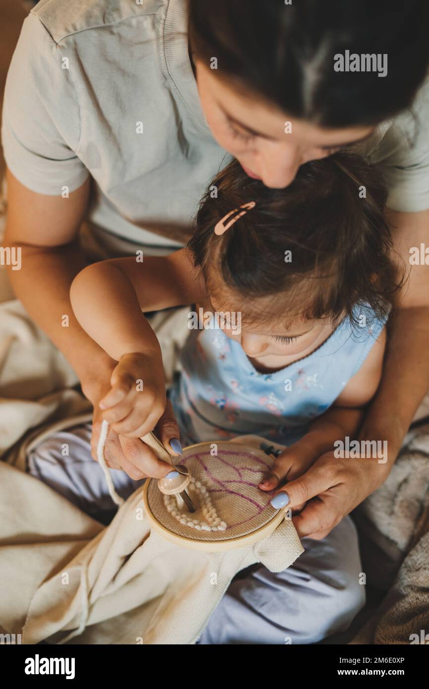 Woman with her child pushing the punchneedle straight down into the ...