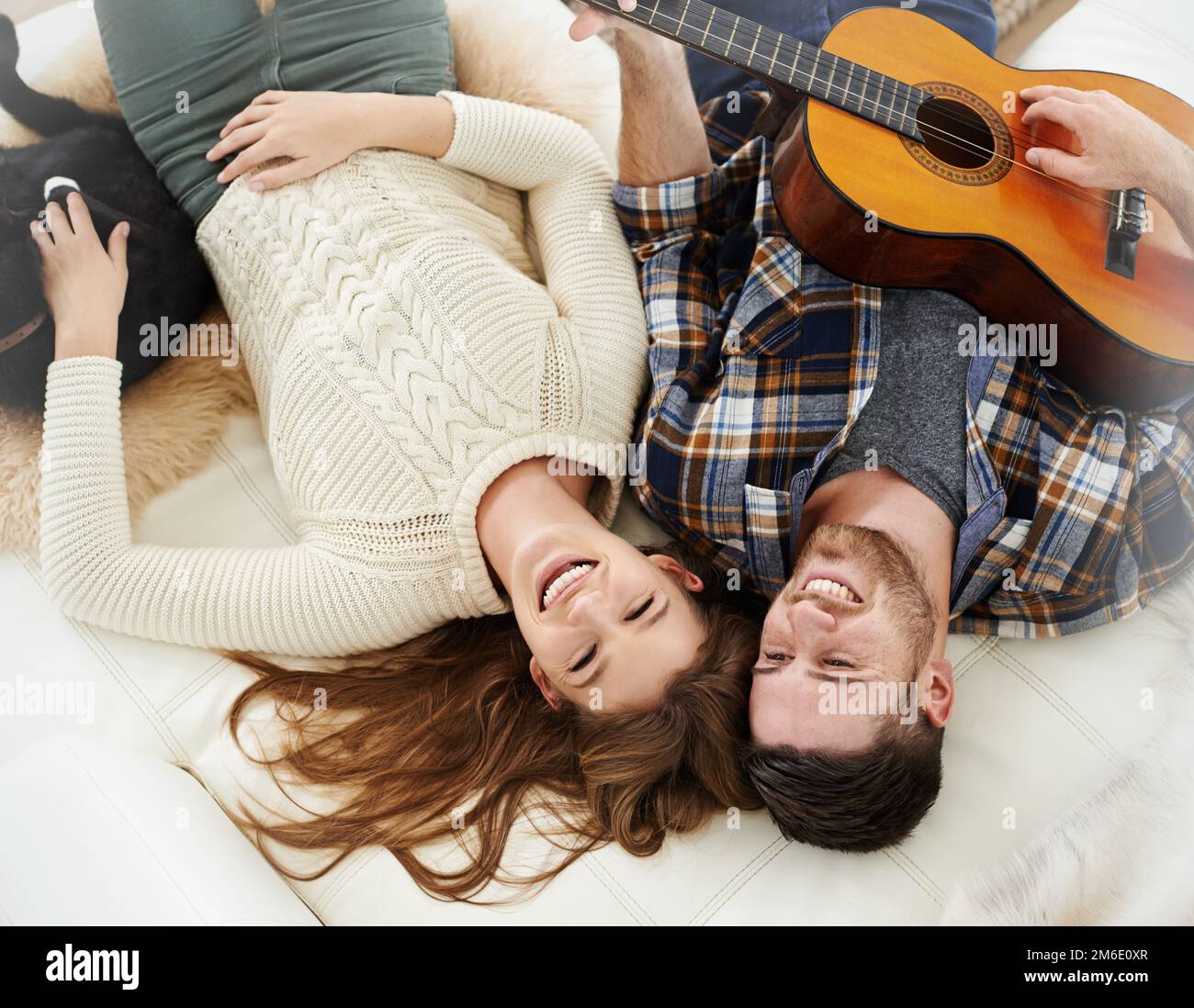 Laughing and loving the music. a young man playing guitar while lying ...