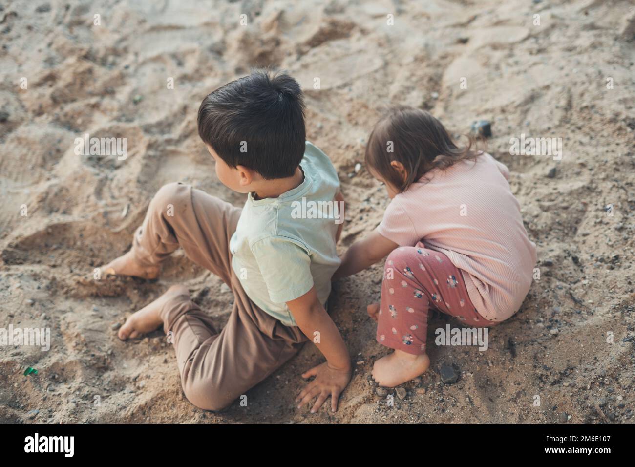 Portrait of two happy kida discovering rocks on the sandy ground in the ...