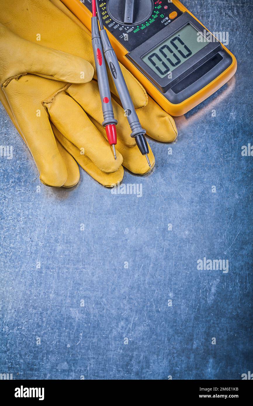 Digital electrical tester protective gloves on metallic background ...