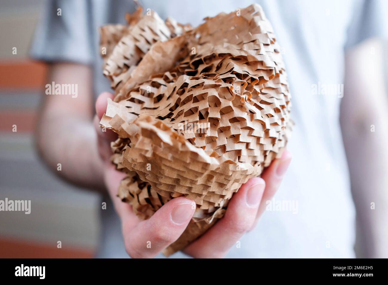 Round ball of brown paper in hand. Thin mesh of brown paper. Side view ...