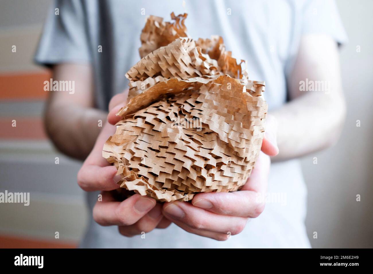 Round ball of brown paper in the hands. Thin mesh of brown paper. Side ...