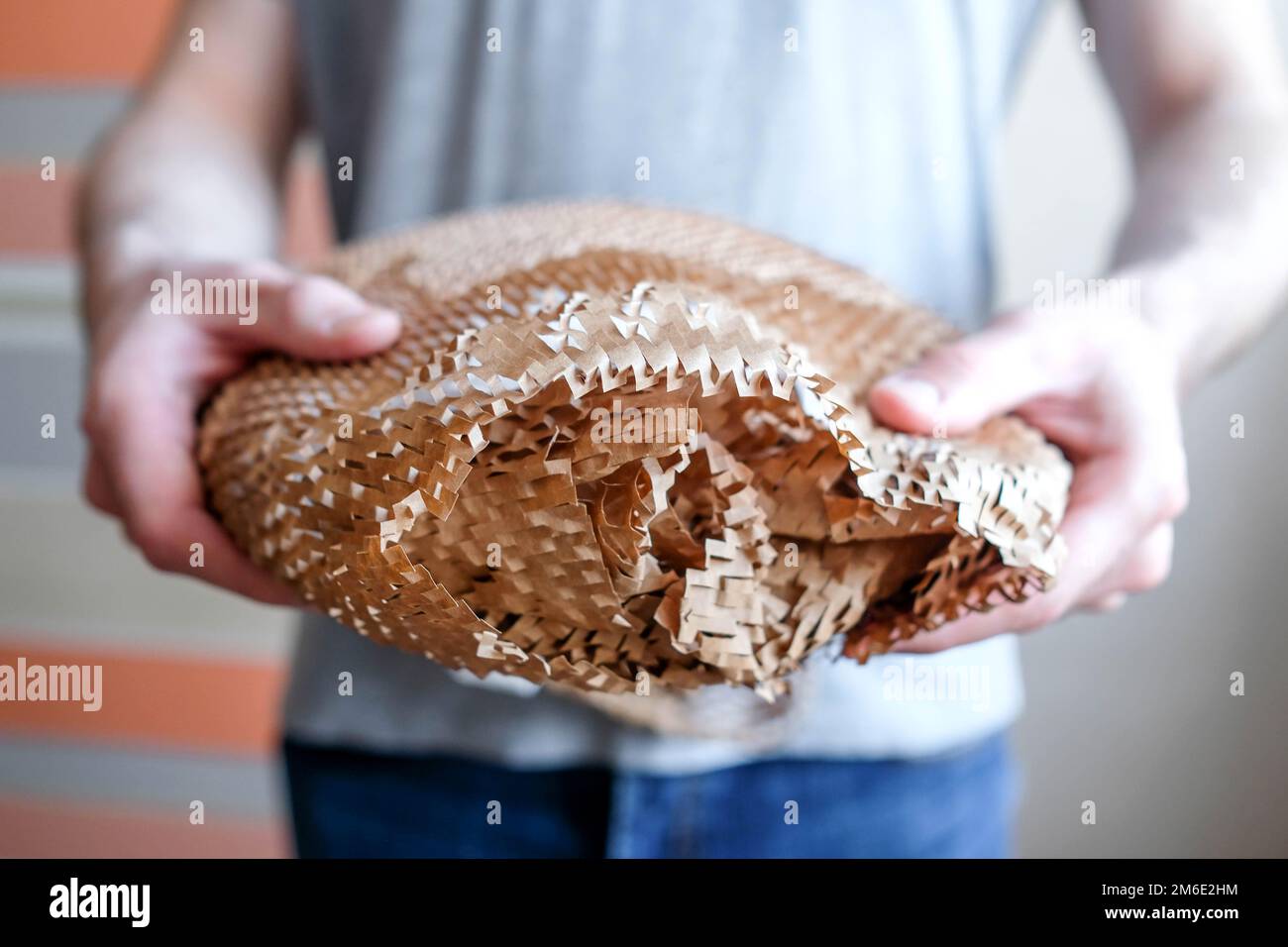 Holds an object in his hand, packed in brown paper with holes. Mesh ...