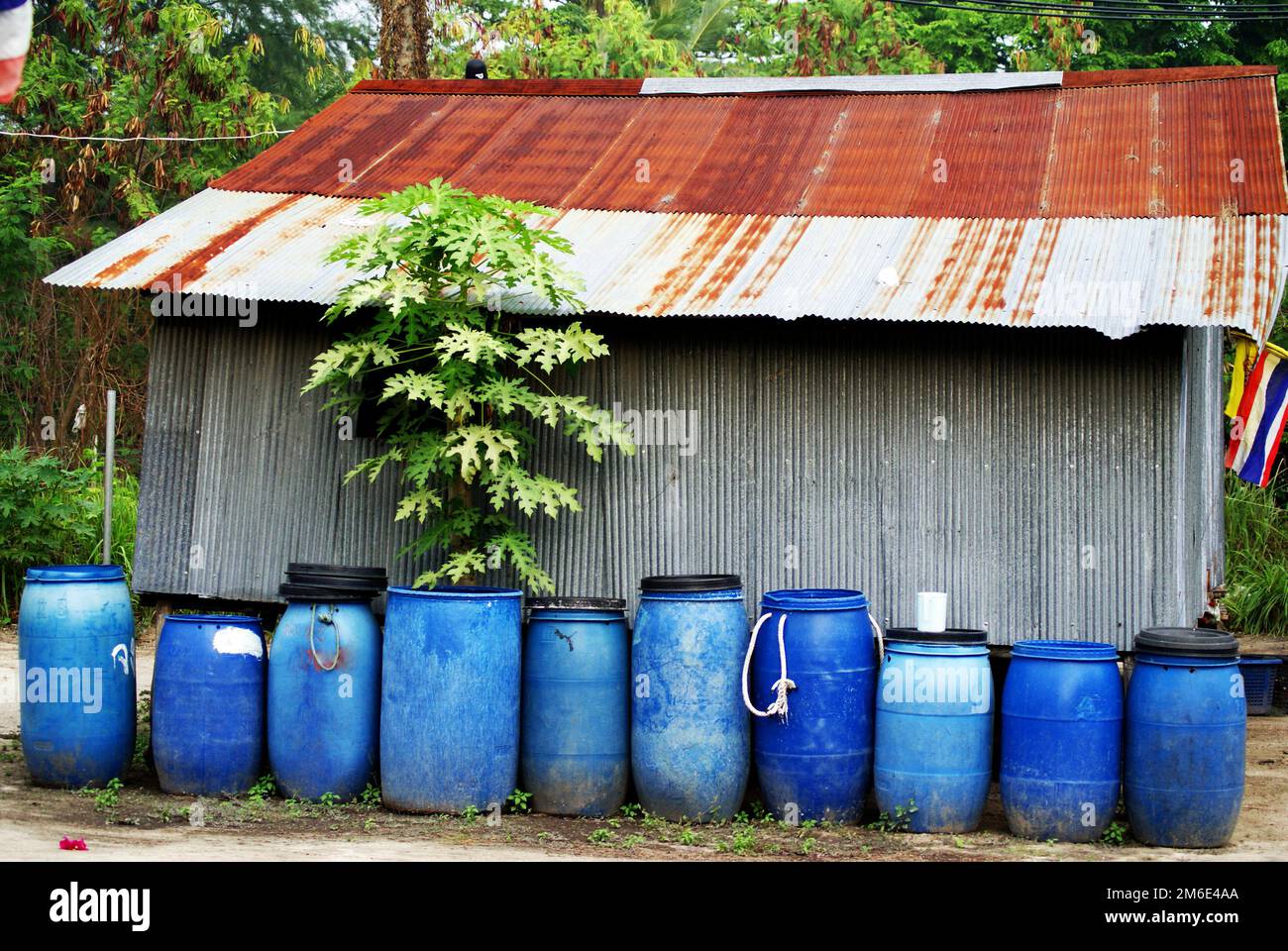 A row of blue plastic barrels in front of a garage building - an ...