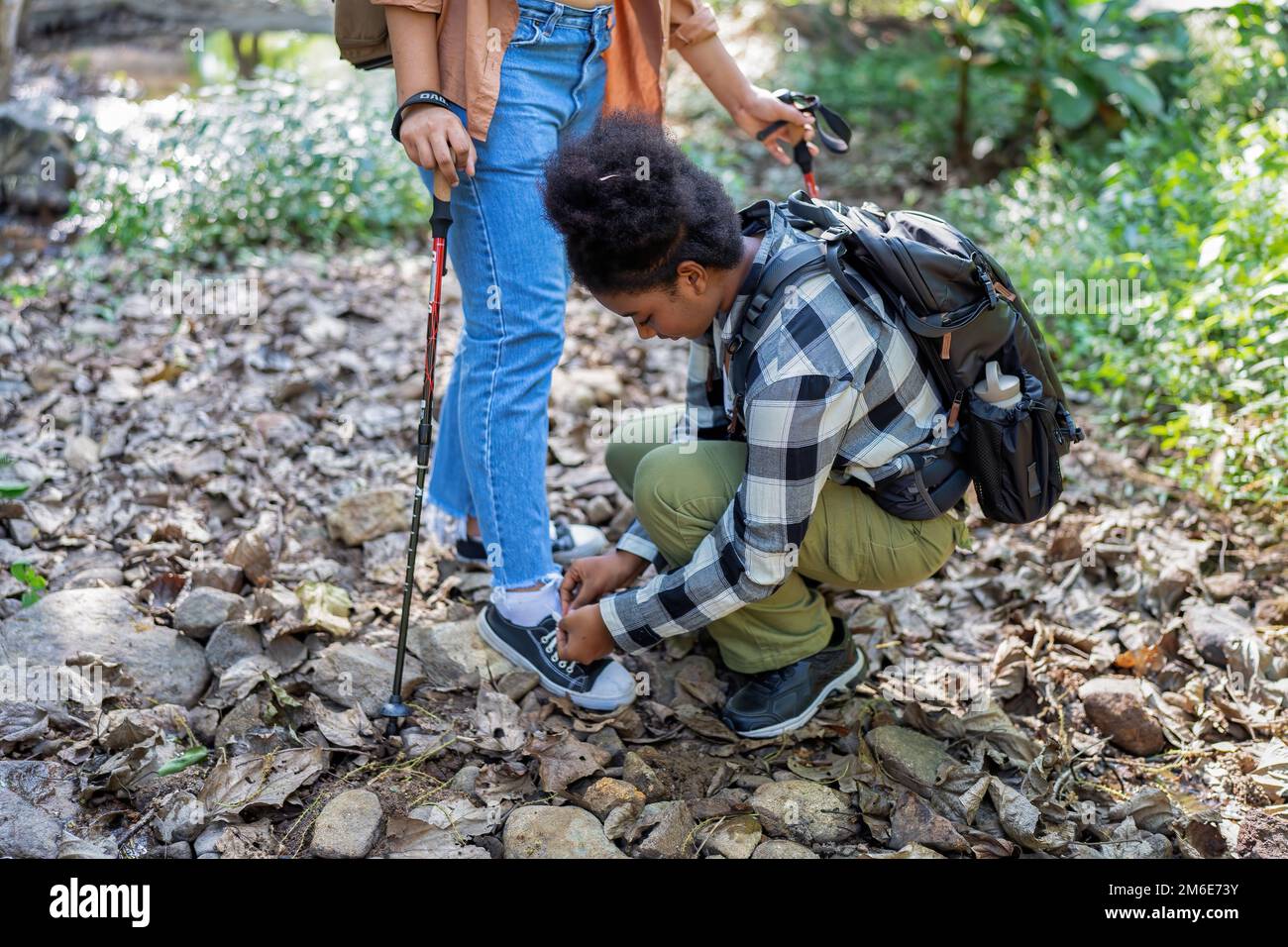 Backpack tourist travel hiking adventure help friend tie up shoelace ...