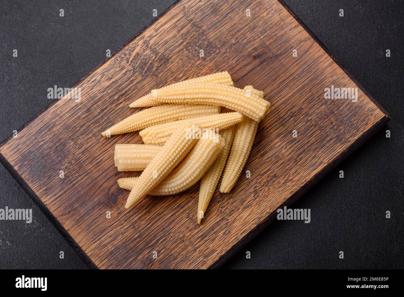A bunch of small white canned corn on a dark concrete background ...