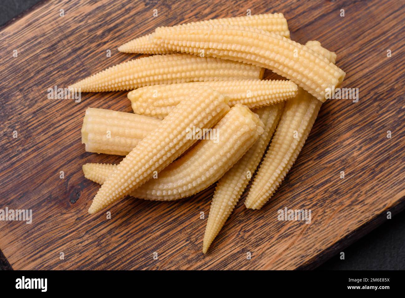 A bunch of small white canned corn on a dark concrete background ...