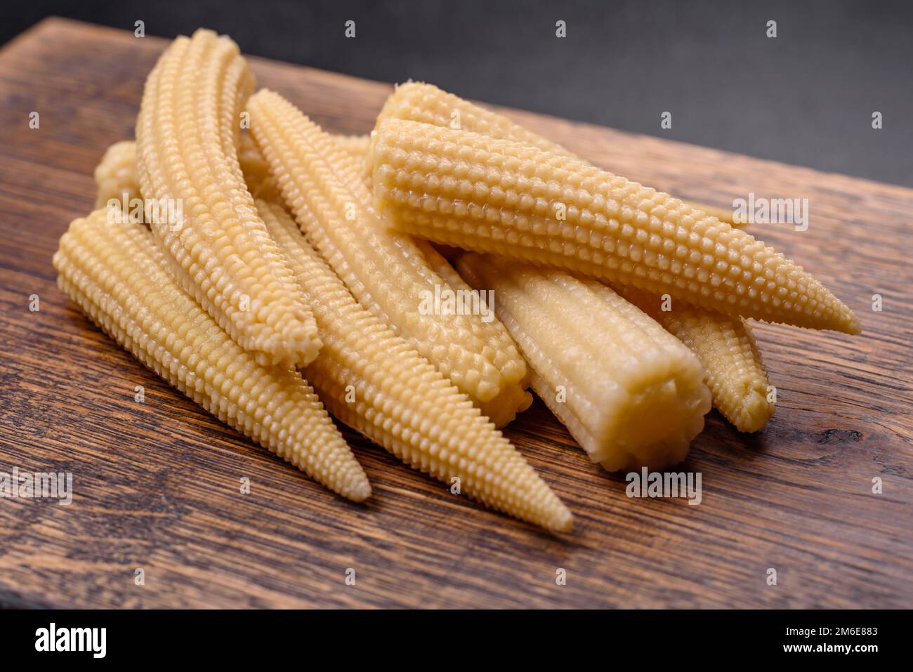 A bunch of small white canned corn on a dark concrete background ...