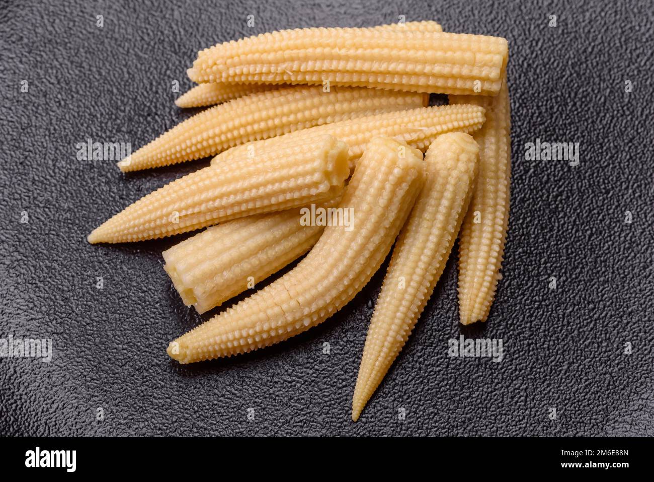 A bunch of small white canned corn on a dark concrete background ...
