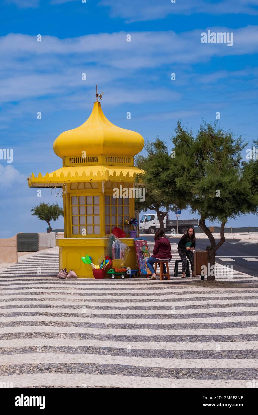 Young Women near a Vibrant Yellow Kiosk / Newstand at the Beach Stock ...
