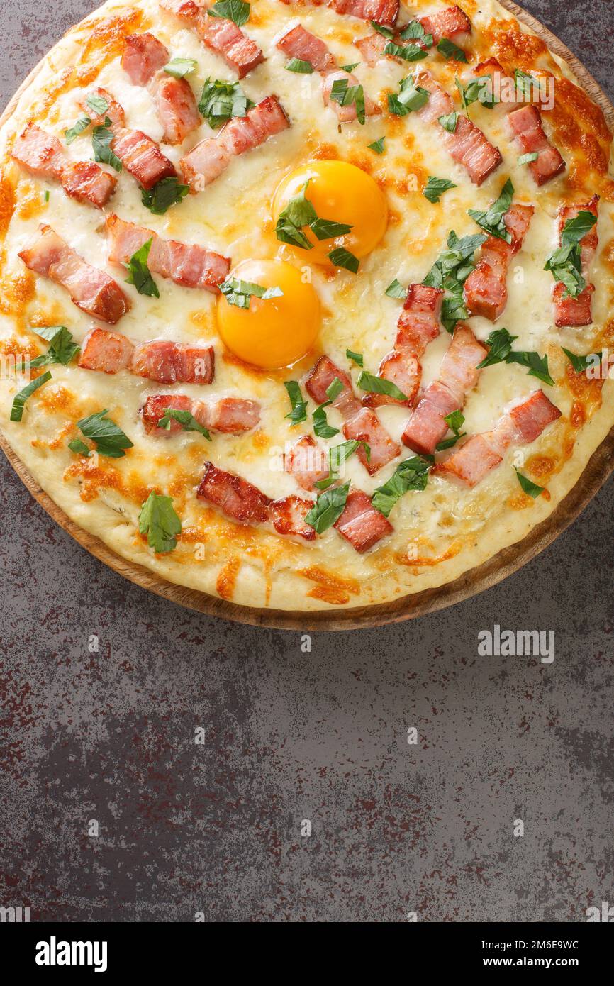 Hot pizza carbonara with bacon, egg, cheese and herbs close-up on a ...