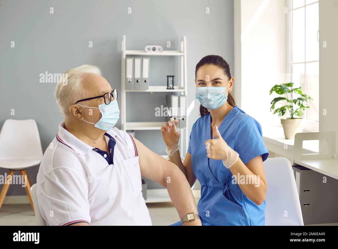 Doctor preparing syringe to vaccinate elderly patient and doing thumb ...