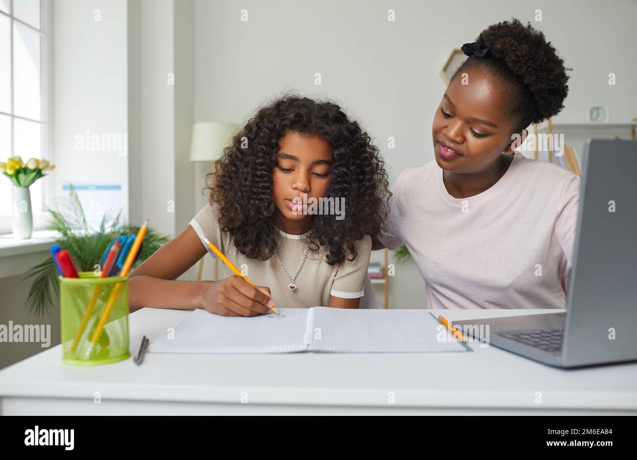 Young African American mother helping her daughter to do school ...
