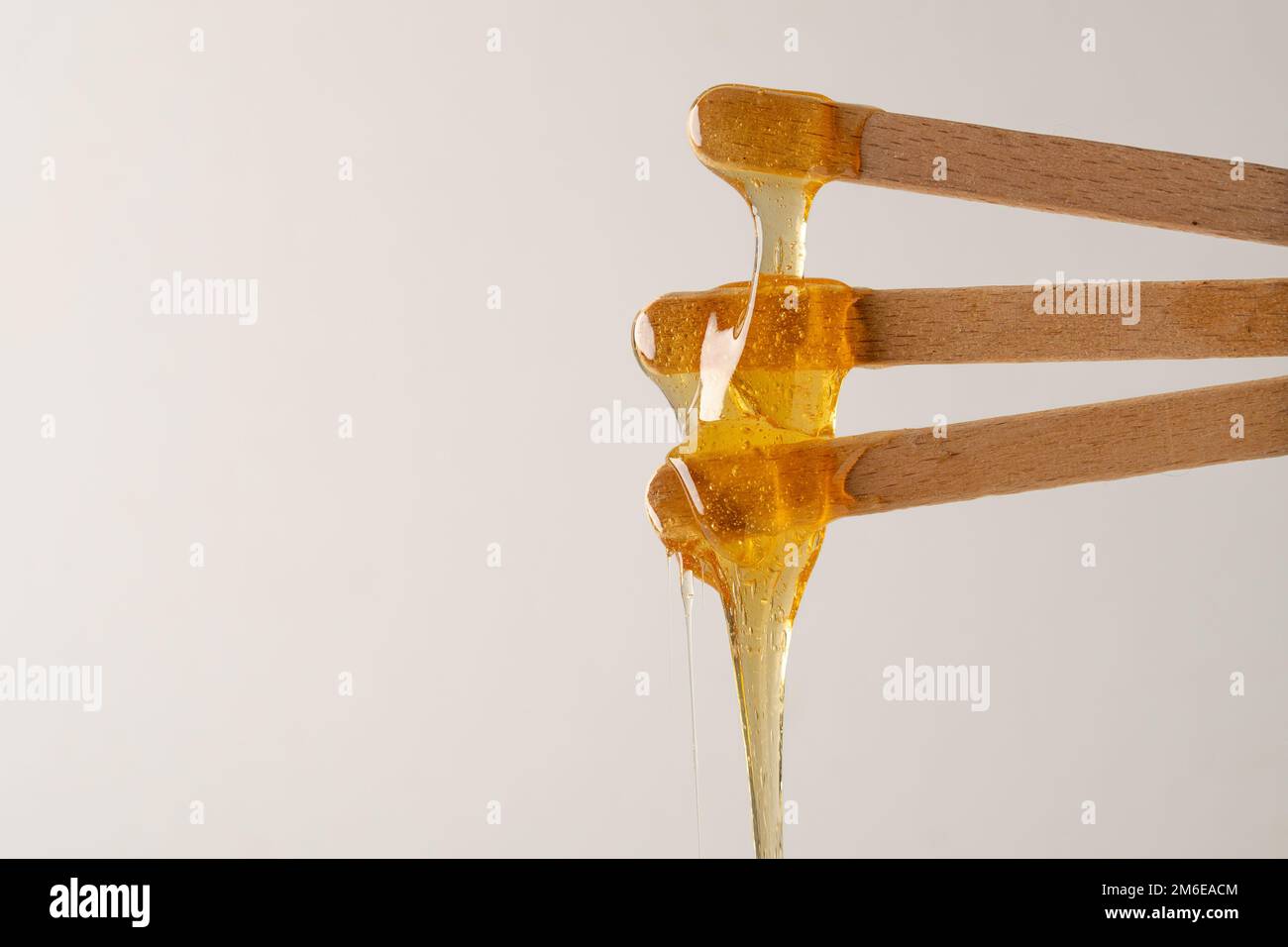 Liquid yellow sugar paste or wax for epilation on three wooden sticks ...