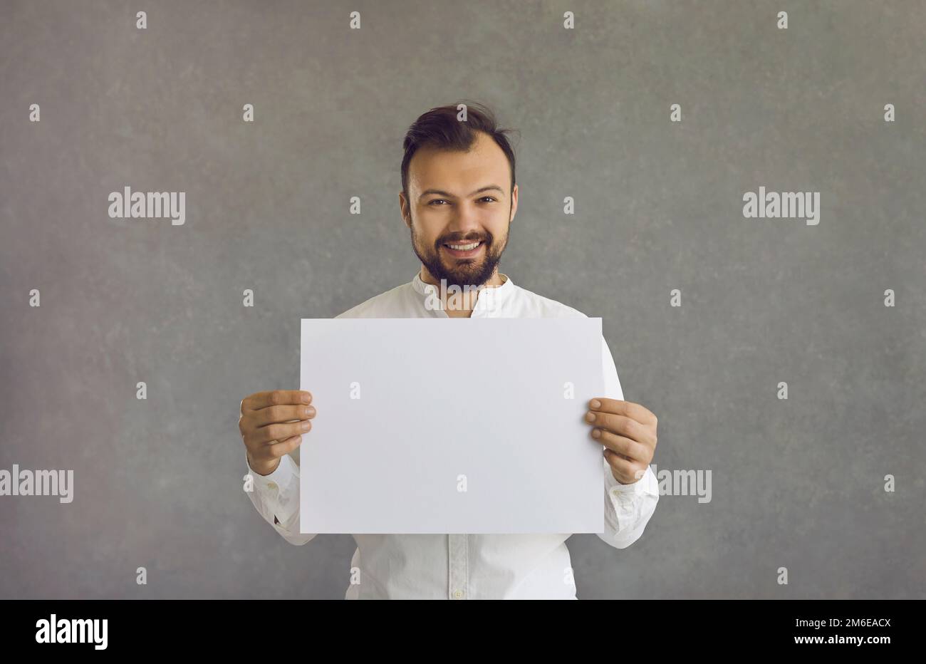 Studio portrait of happy young man smiling and holding blank mockup ...