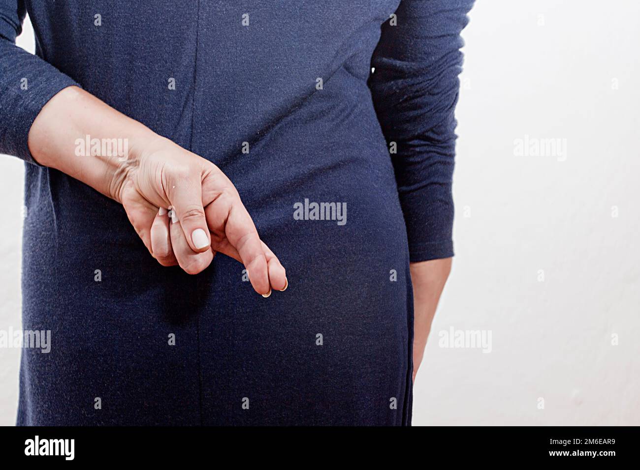 Crossed fingers behind Stock Photo - Alamy