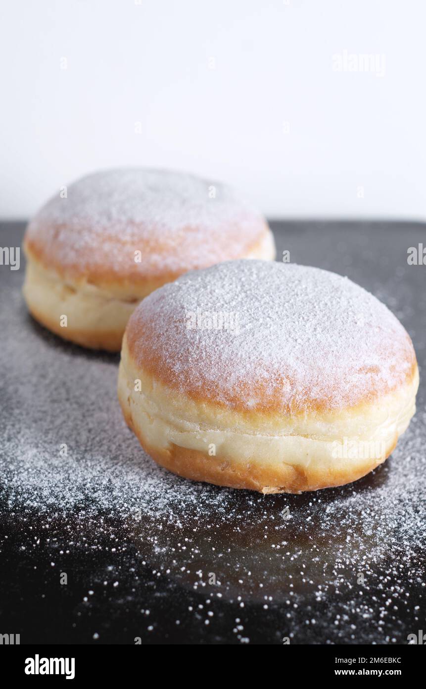 Doughnuts dusted with icing sugar on black metal background Stock Photo ...