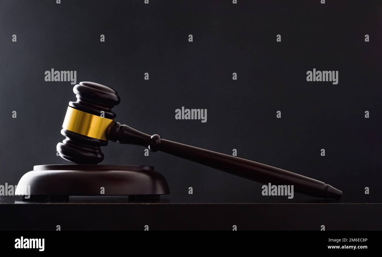Front view of gavel on wooden base on a black table and background ...
