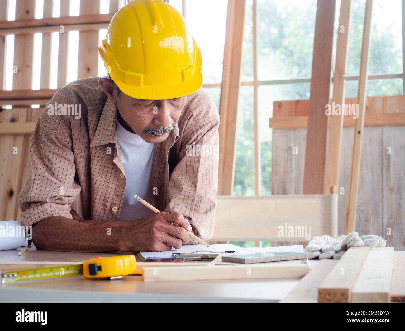 Happy senior carpenter using a tape measure for measuring woodwork in ...