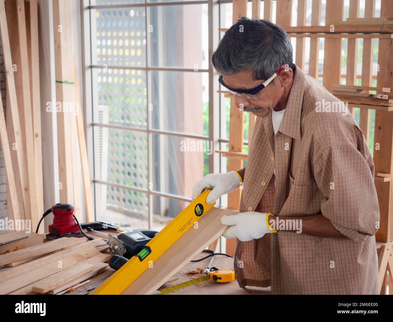 Accuracy and quality. Happy senior carpenter checking the level of a ...