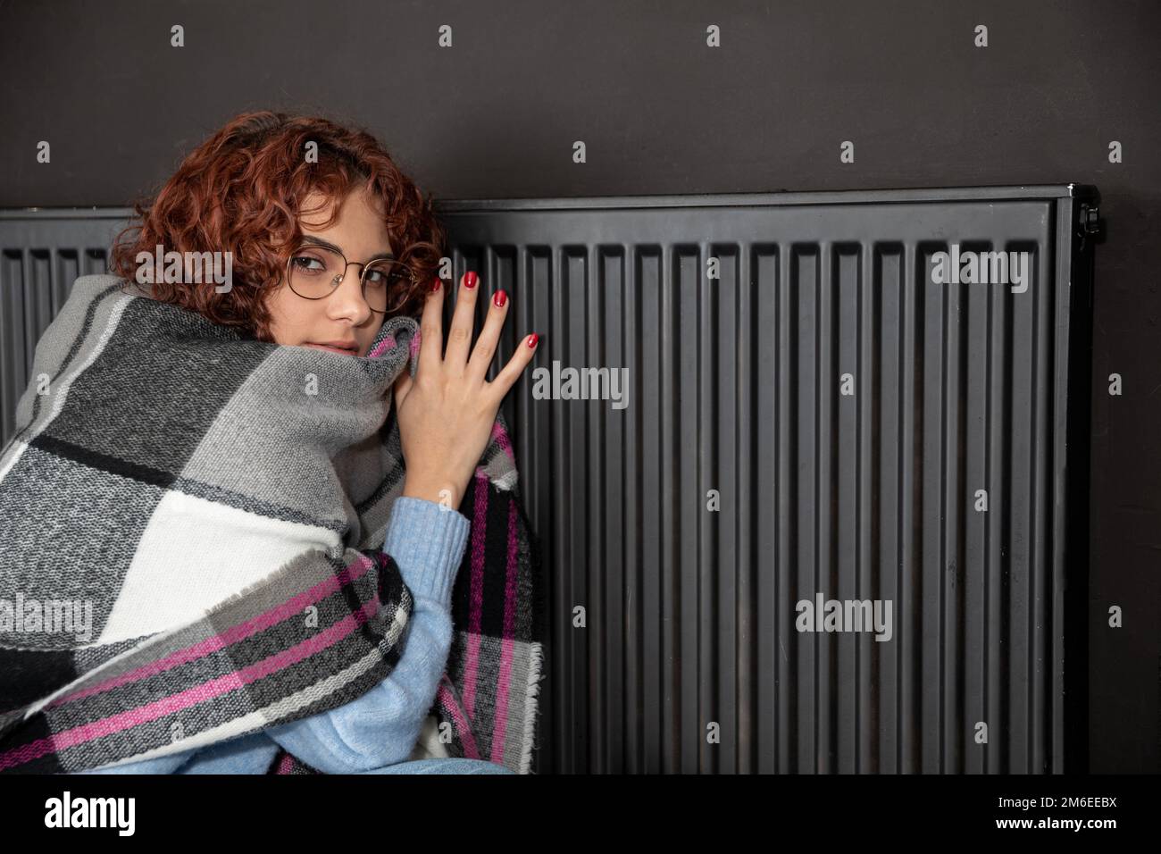 A girl huddled around a hot radiator. The first start of the central ...