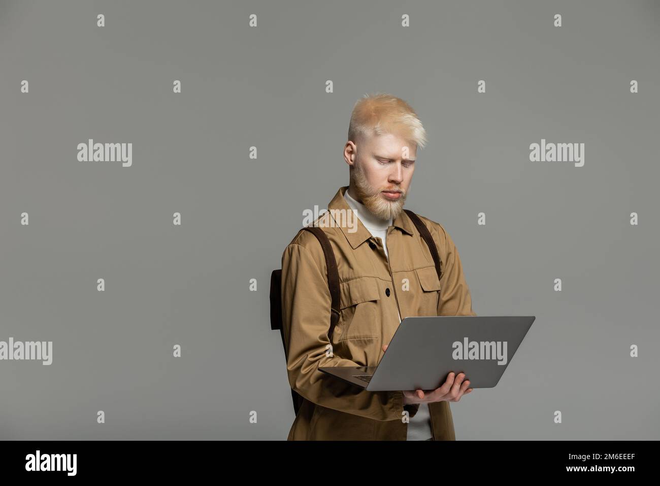 albino student with backpack using laptop while studying online ...