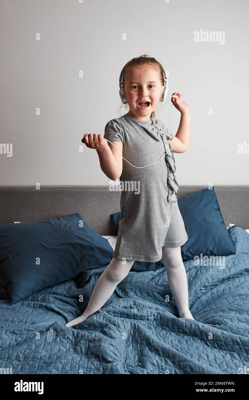 Little girl singing holding headphones cord imitating herself a real ...