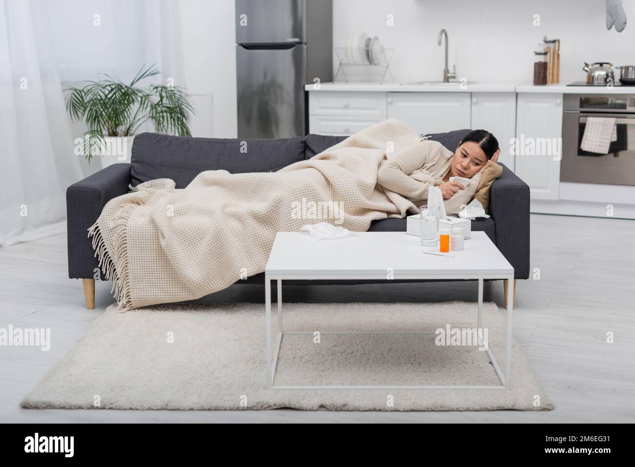 Sick asian woman suffering from runny nose and holding napkin near ...