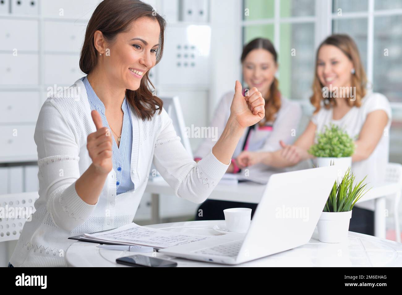 young women sit at the table and work in a modern office Stock Photo ...