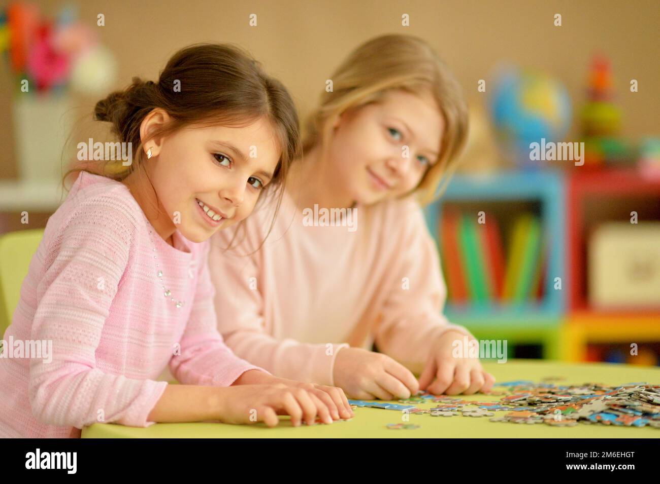 little girls collecting puzzle pieces while sitting at table Stock ...