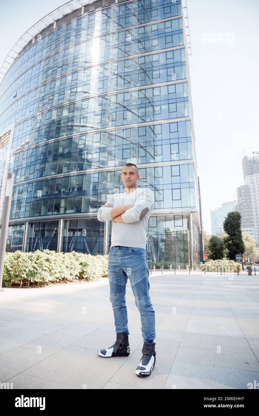 The guy is standing with his hands folded. Young man near the glass ...