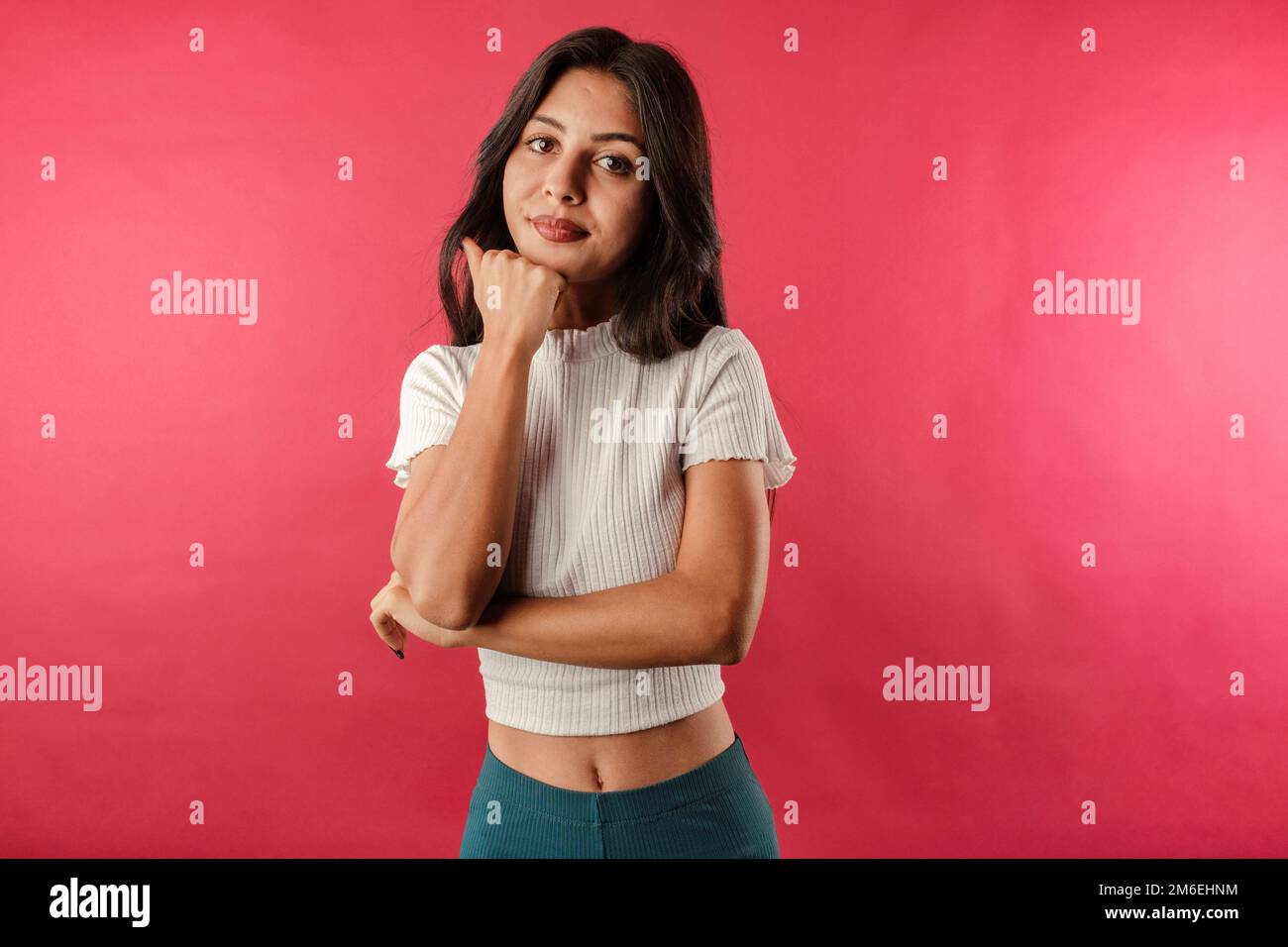 Brown-haired woman wearing white ribbed crop isolated over red ...