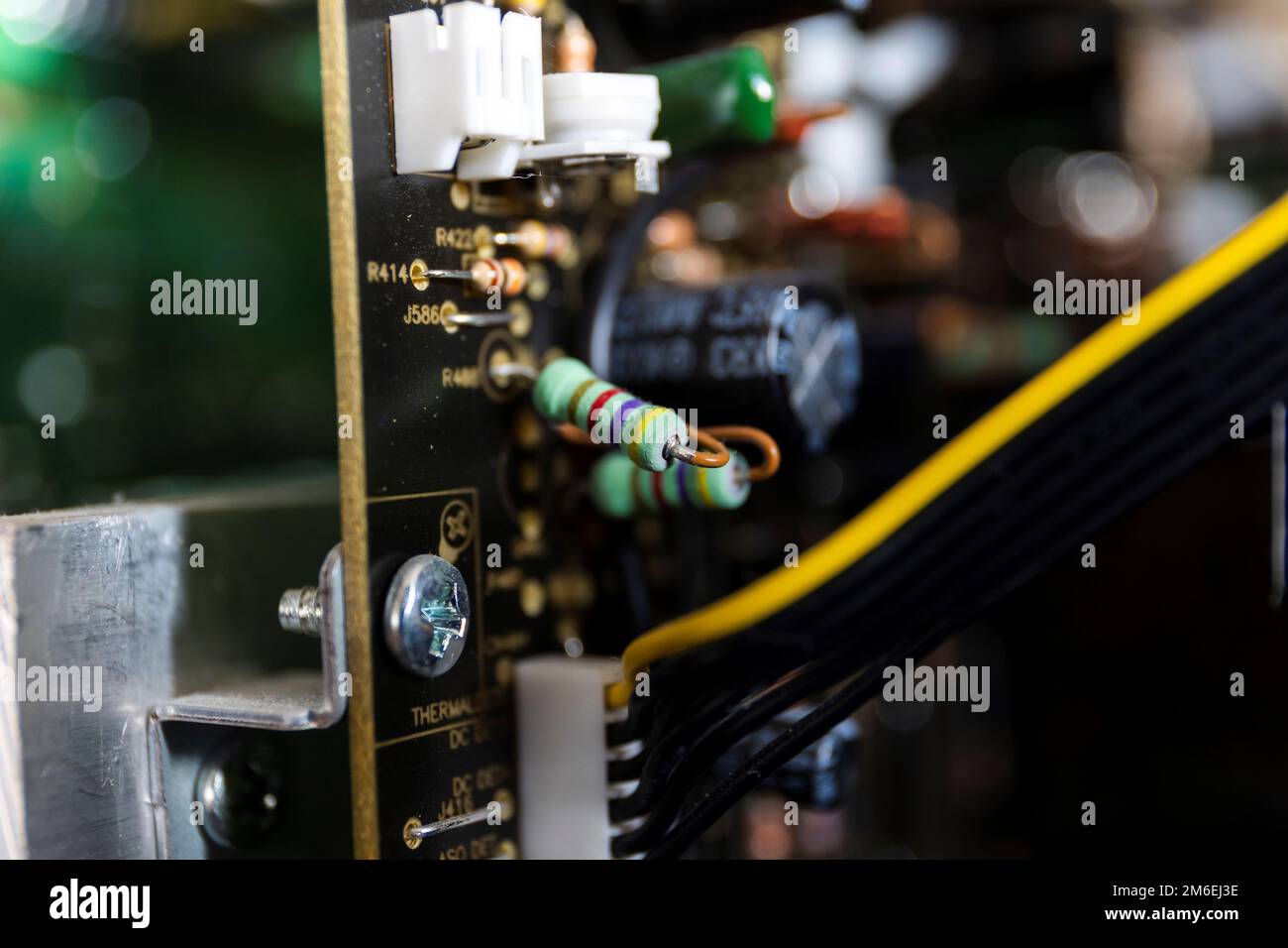 A close up portrait of some resistors standing a bit crooked on a black ...
