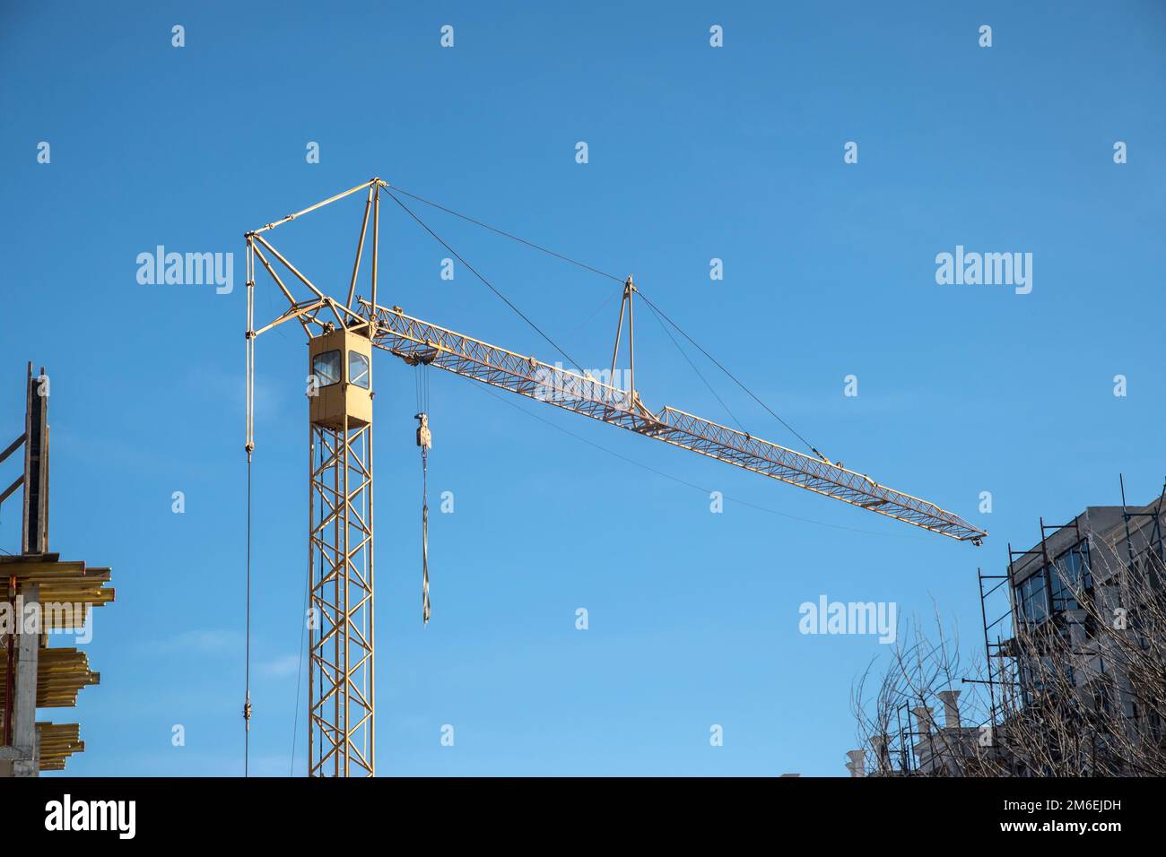 Tower crane between buildings in construction closeup on blue sky ...