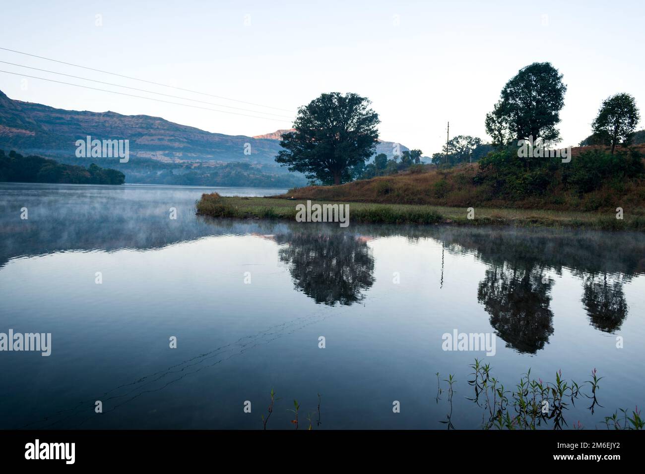 Beautiful reflection of a landscape of trees, hills, and water at Arthur Lake in Bhandardara in ...