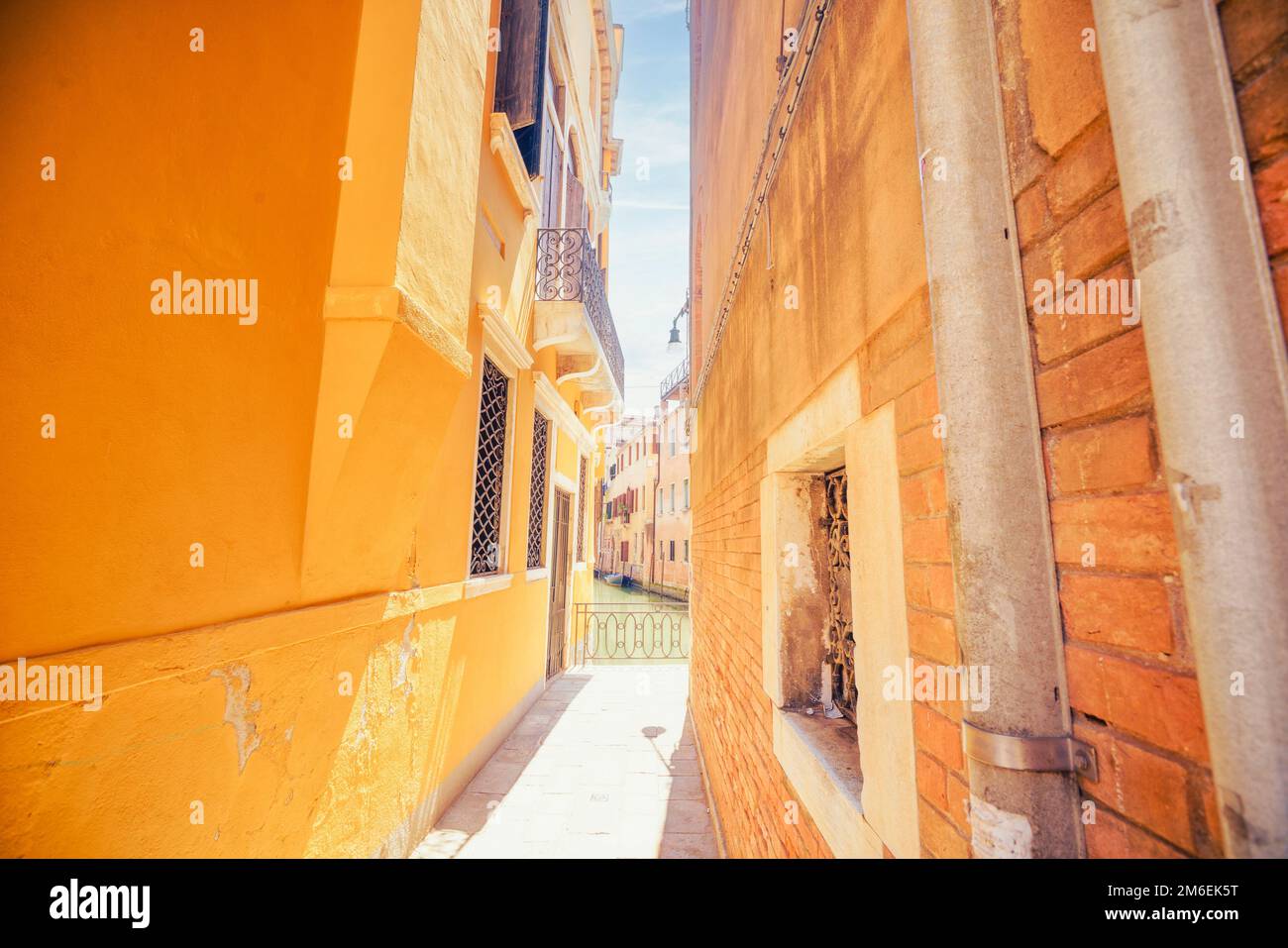 Yellow brick buildings in Venice, Italy in a small passage towaeds the ...