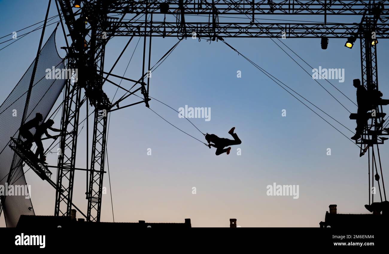 silhouettes of trapeze artists acrobats on the metal scaffolding at ...