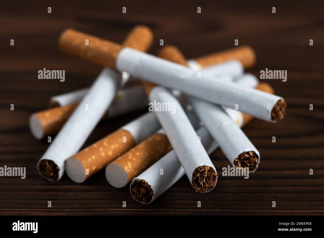 Close up of a hope smoking cigarettes. Cigarette filter tubes on wooden ...