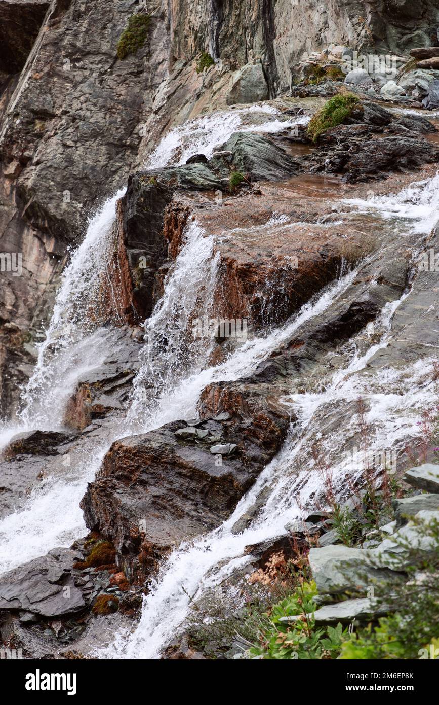 Super contrasting vertical shot of flowing and foaming water of alpine ...
