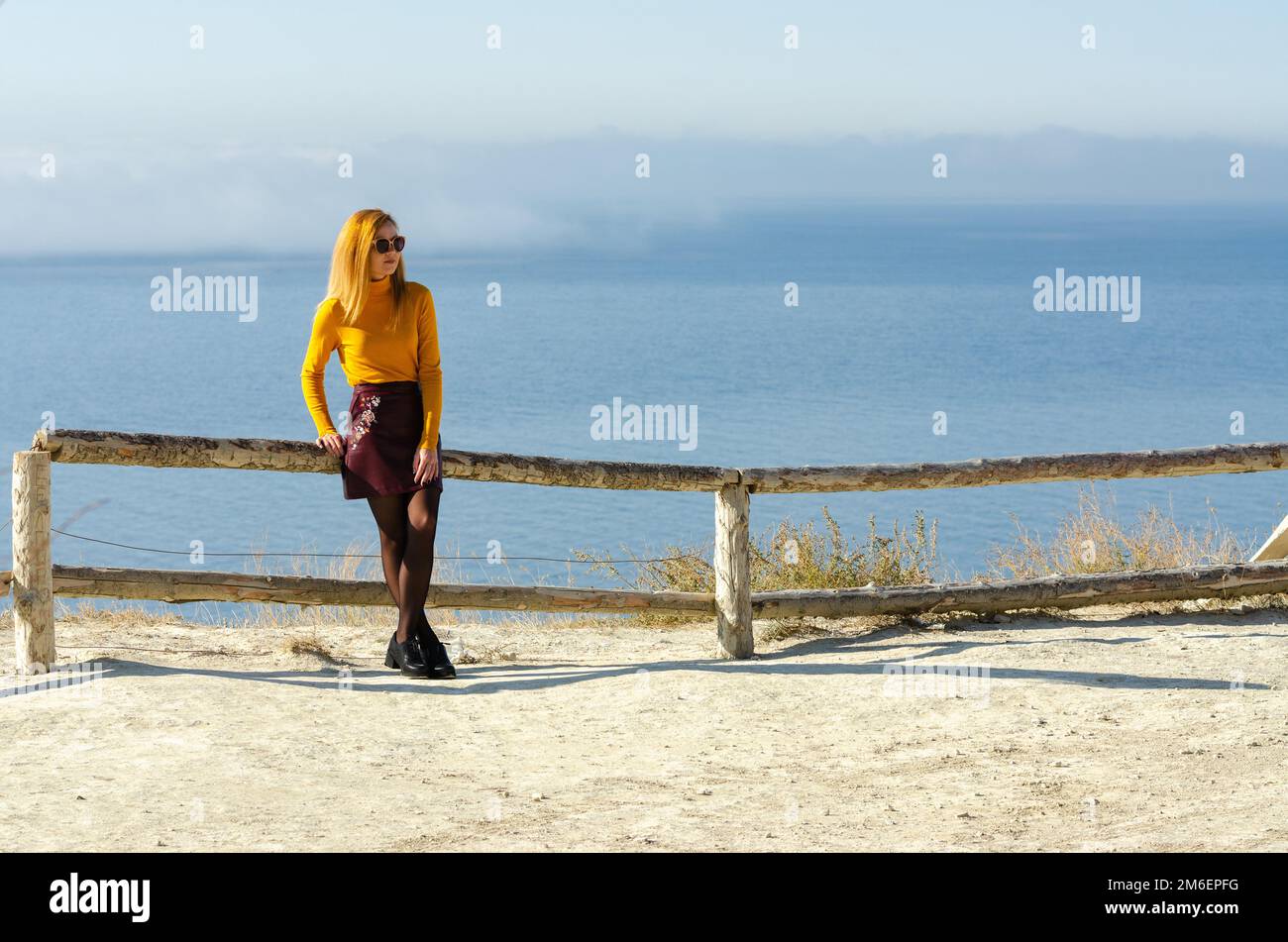 The girl sat down on a fence made of a wooden frame against the ...