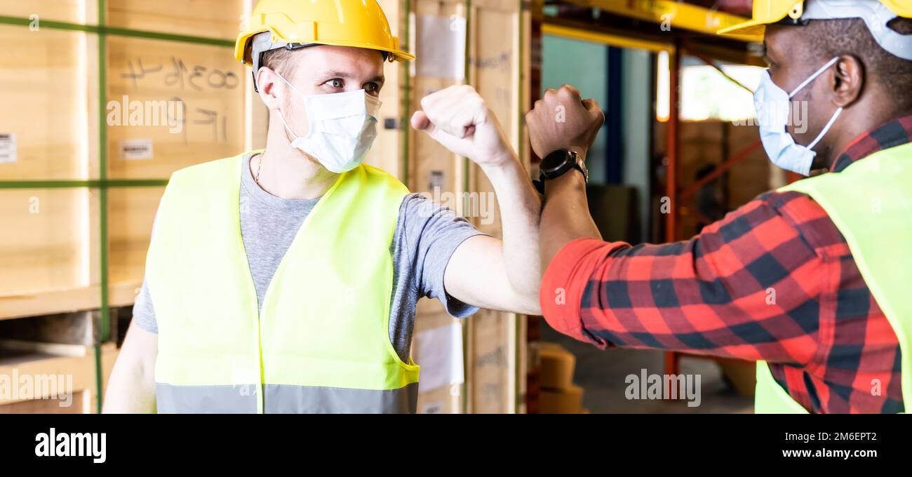 Interracial warehouse worker with face mask do elbow bump greeting ...