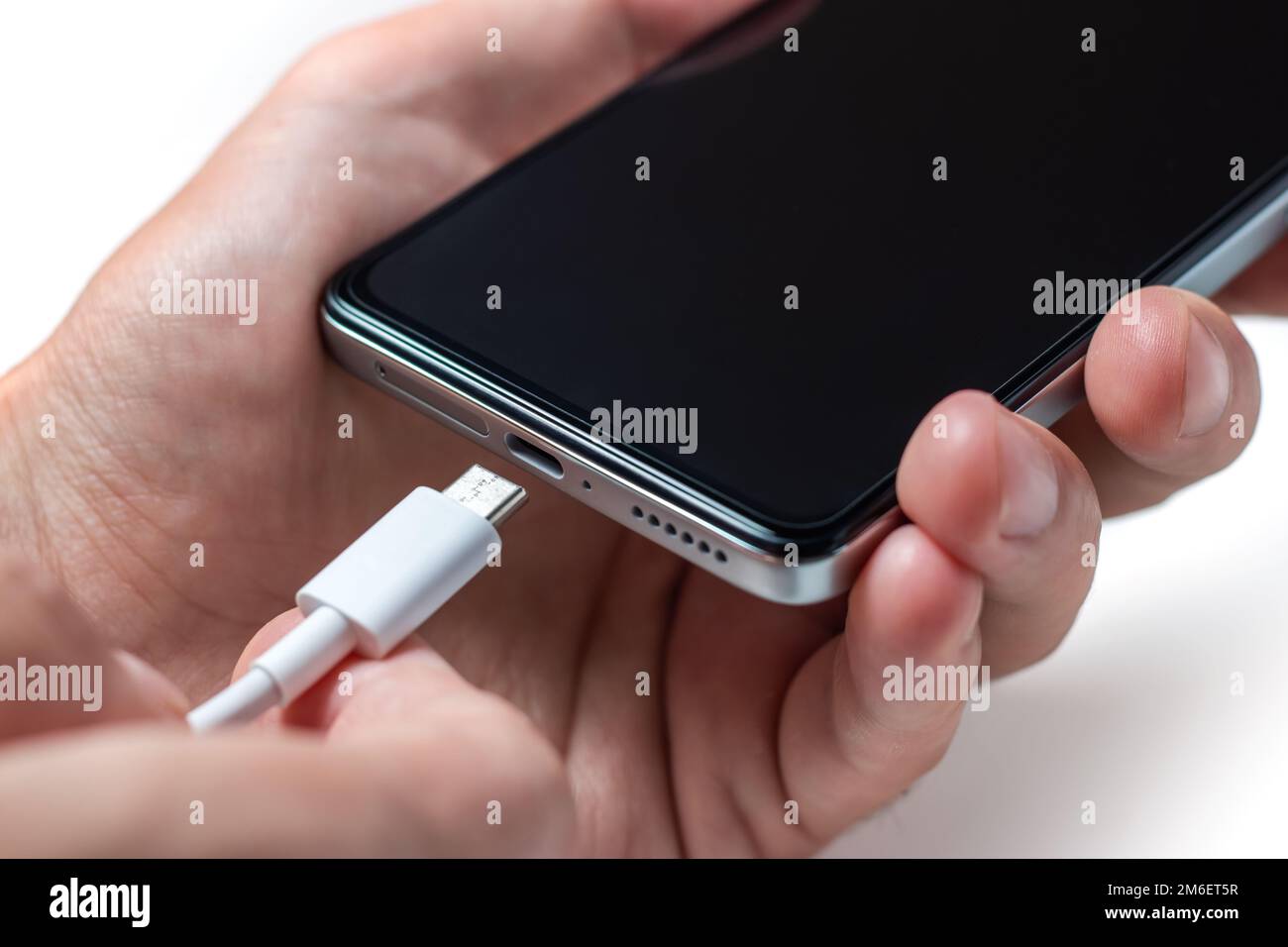 Charging a smartphone via a USB cable and a power supply. A black ...
