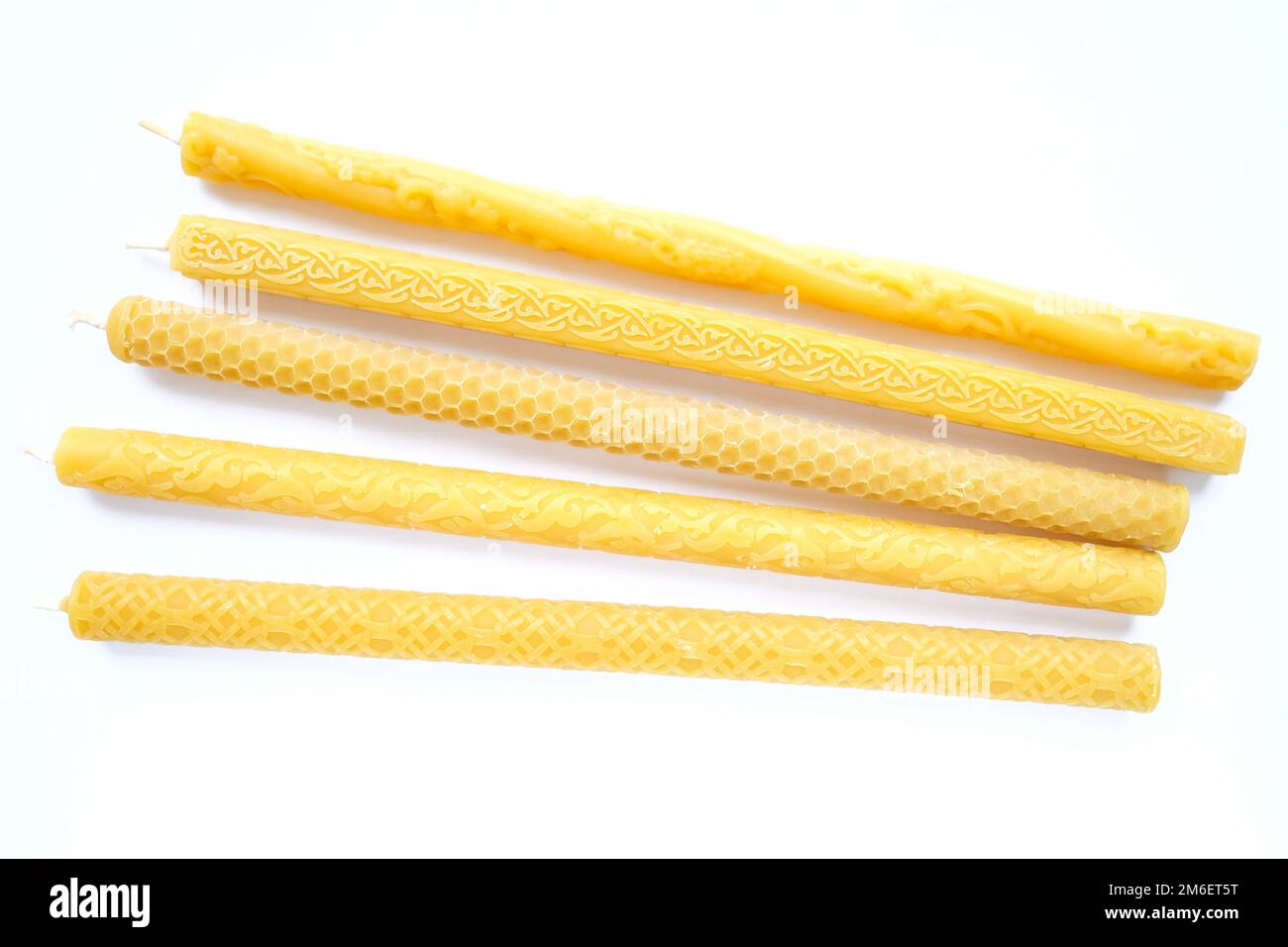 Large yellow candles with different cut patterns on white. Lie side by ...