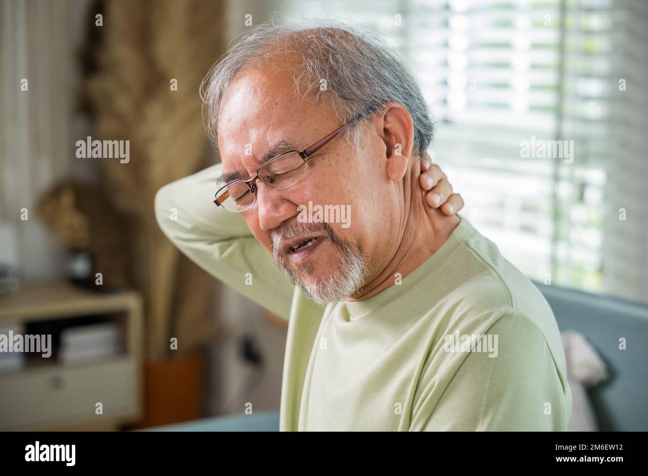 Old man suffering from nape neck pain at home Stock Photo - Alamy
