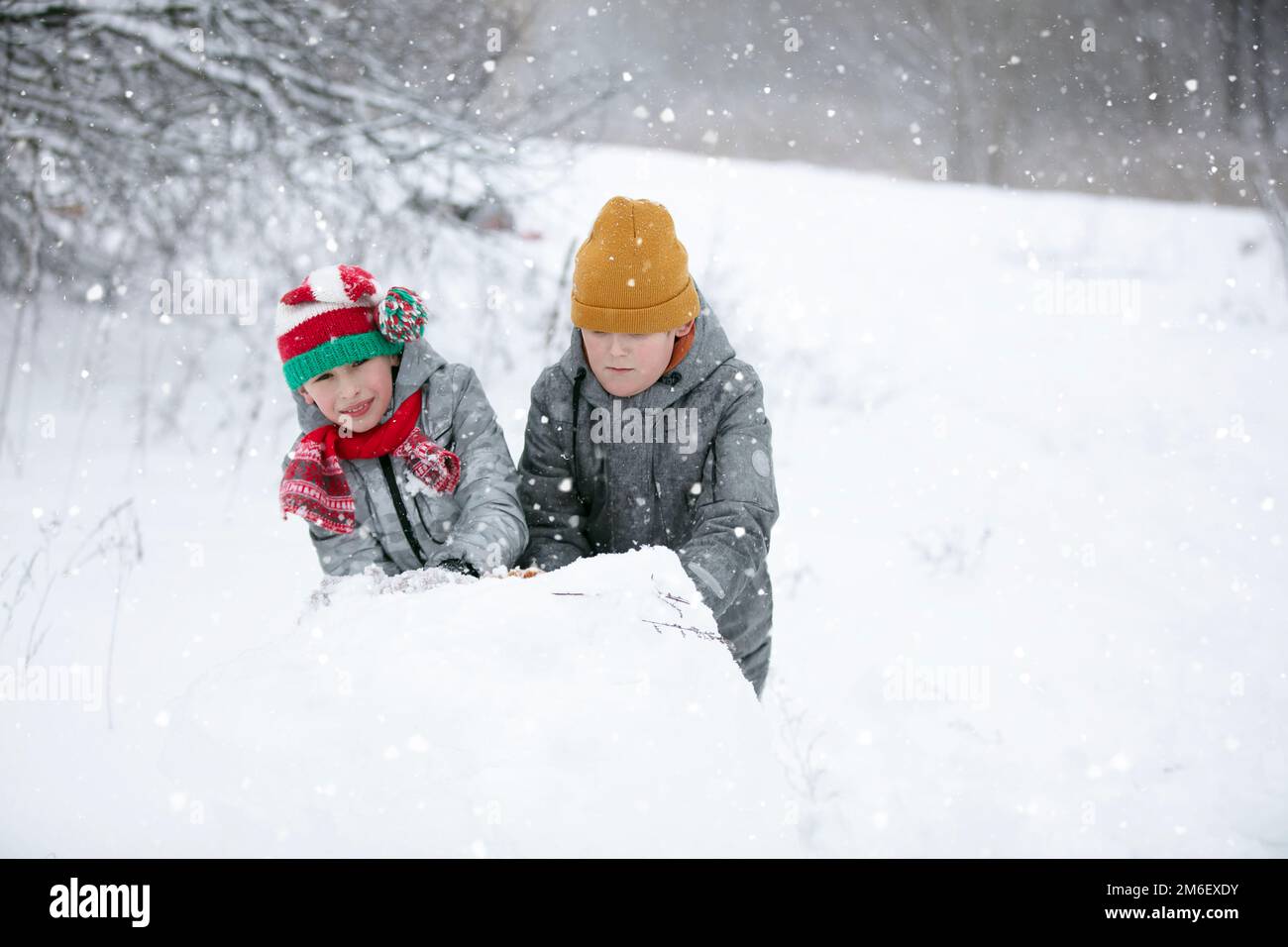 Two boys are playing in the snow. Children sculpt from snow. Play on a ...