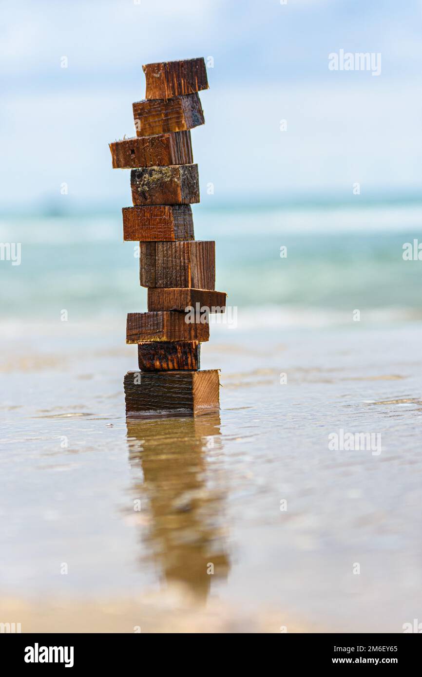 A tower made of wet pieces of wood stands on the wave-laden seashore ...