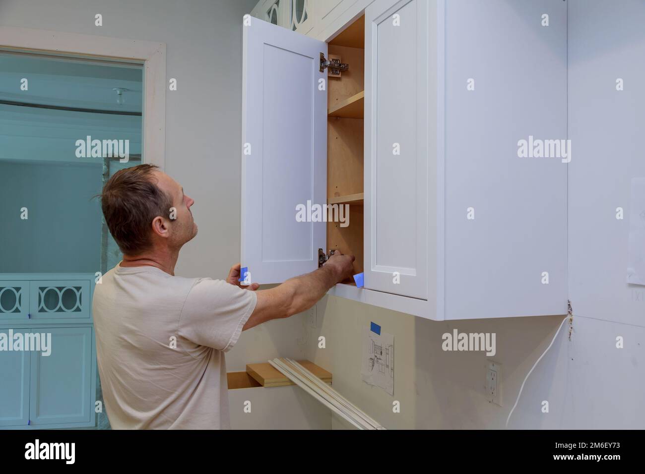 Worker working on door of new kitchen cabinet in new house Stock Photo ...