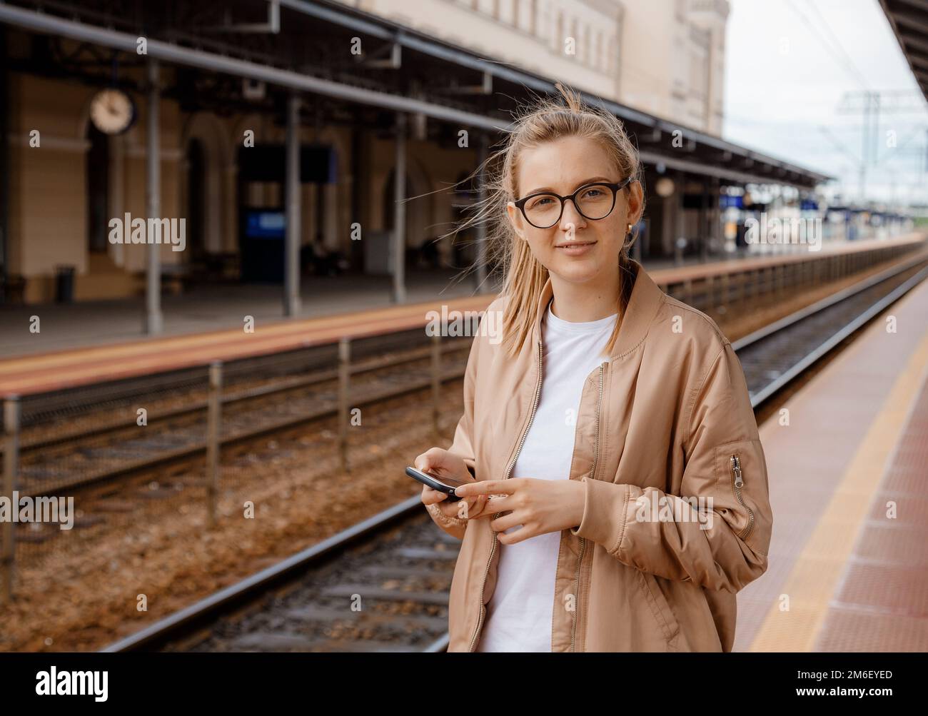Woman with glasses on the platform near the train. Girl with a cell ...
